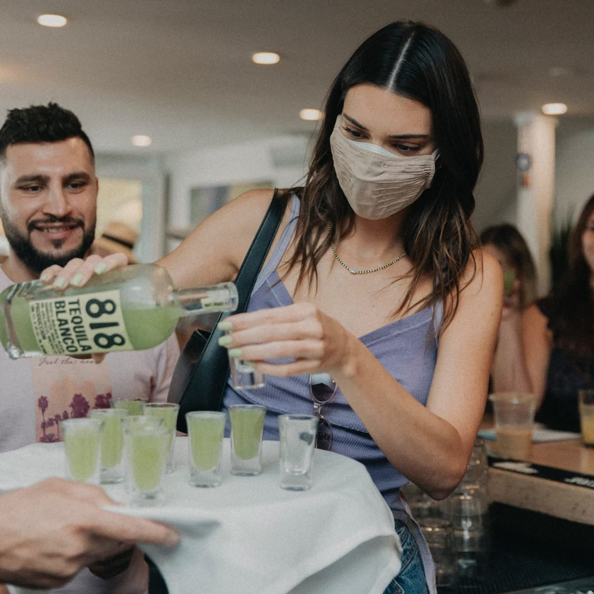 Kendall Jenner stands behind a bar to serve her tequila